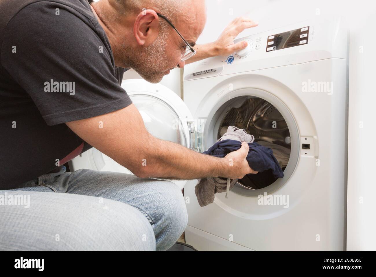 Male loading the washing machine with dirty clothes Stock Photo - Alamy