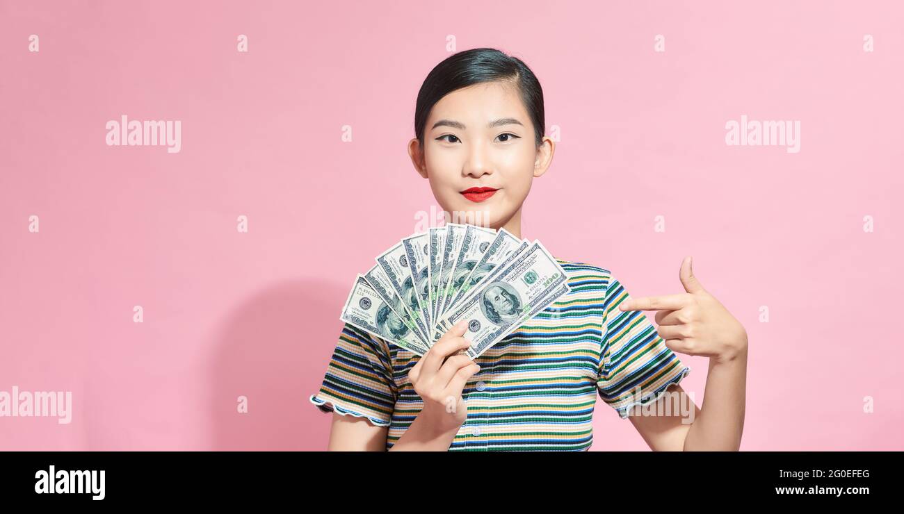 Smiling funny young asian woman standing pointing index finger on fan ...