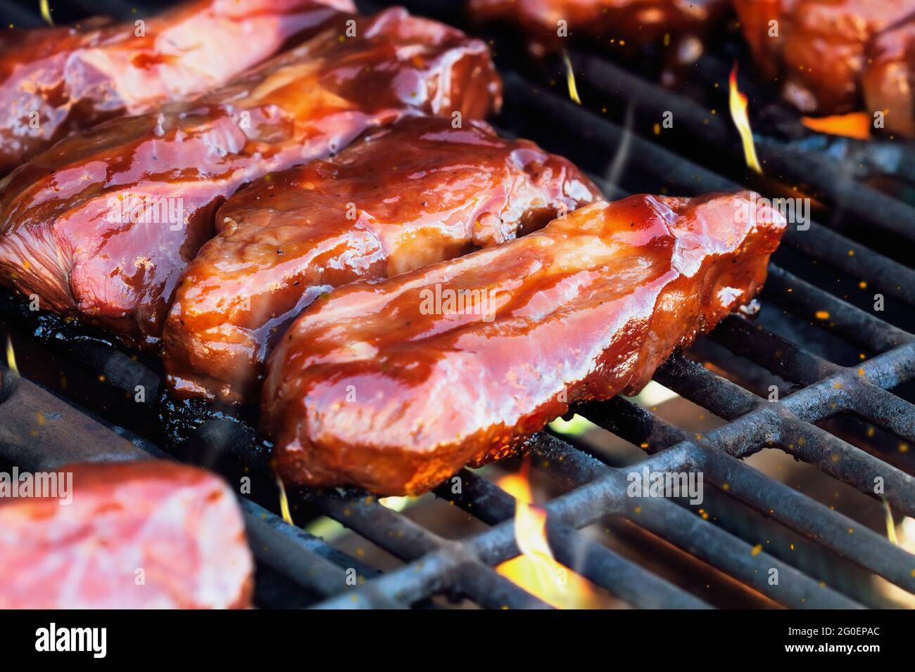 Boneless beef ribs grilling over flames with tangy barbecue sauce for a ...