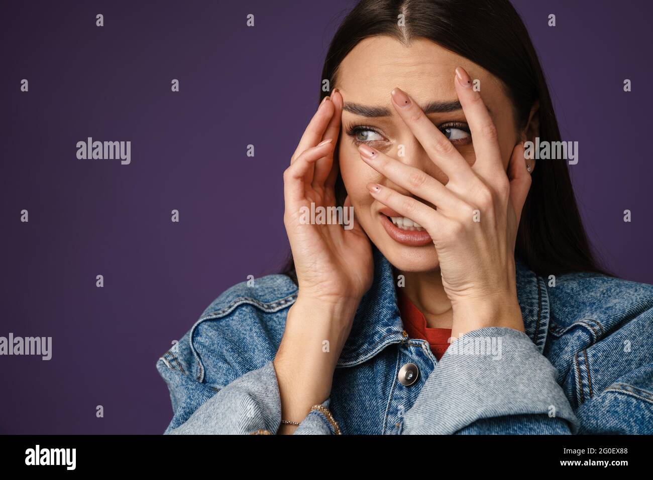 Scared beautiful brunette girl covering her face and looking aside ...