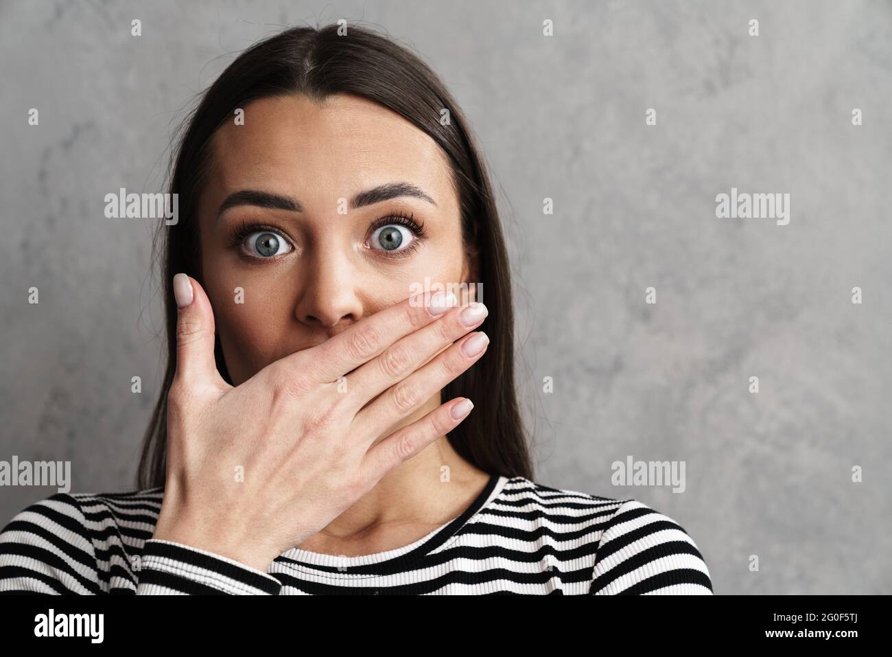 Beautiful shocked young woman covering her face with hand isolated on a ...