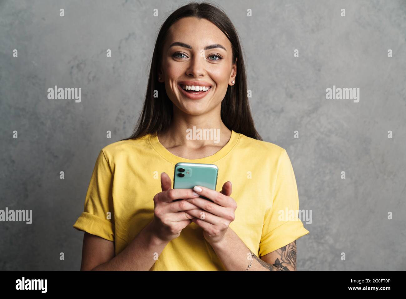 Happy cheerful woman using mobile phone isolated over gray background ...