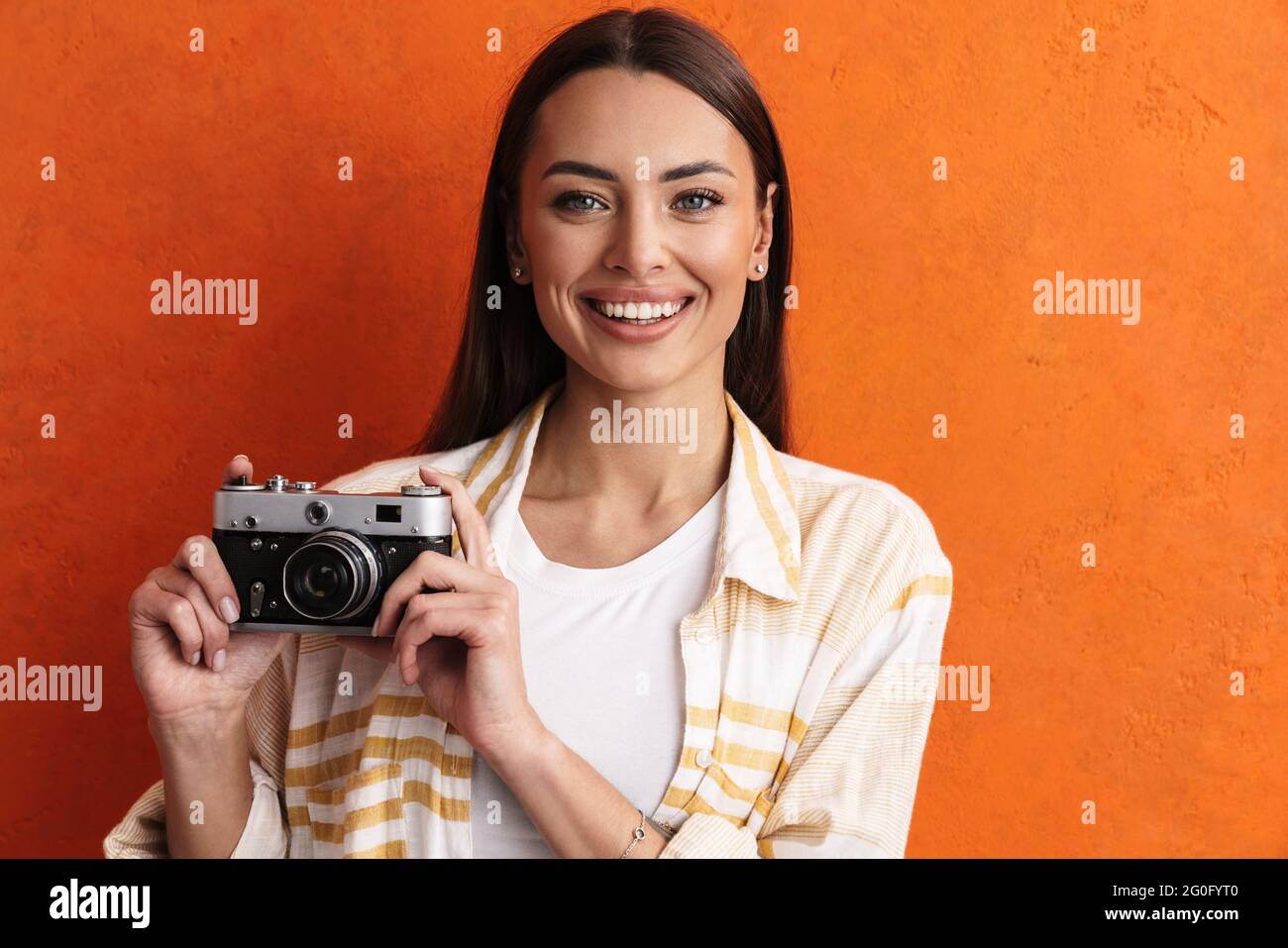 Happy cheerful woman holding photo camera isolated over gray background ...