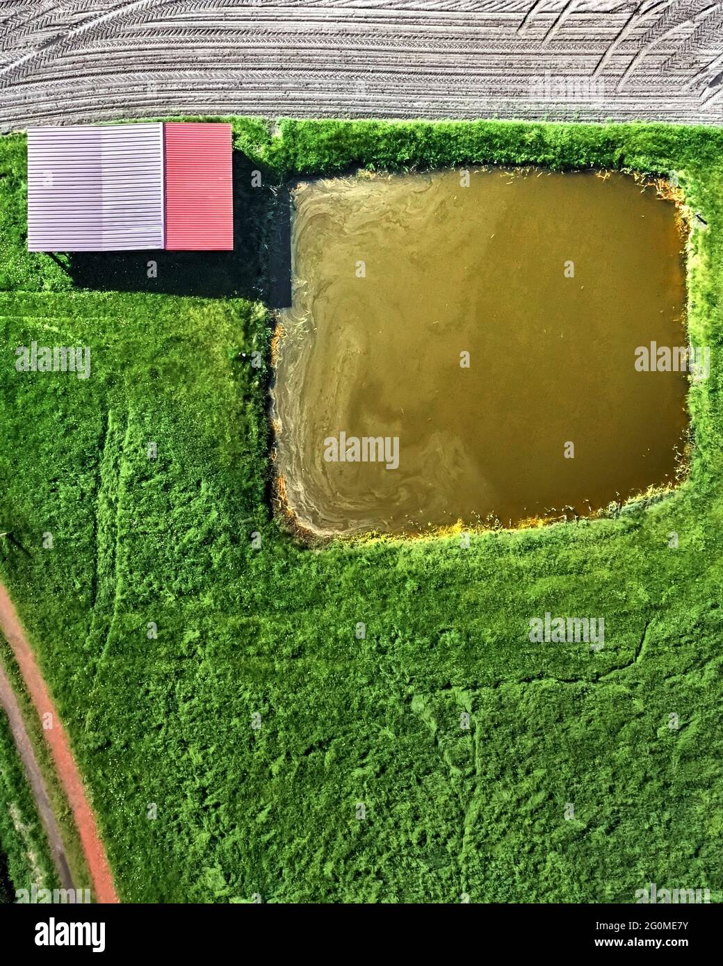 Aerial view of a shed behind a small artificial fish pond on a path ...