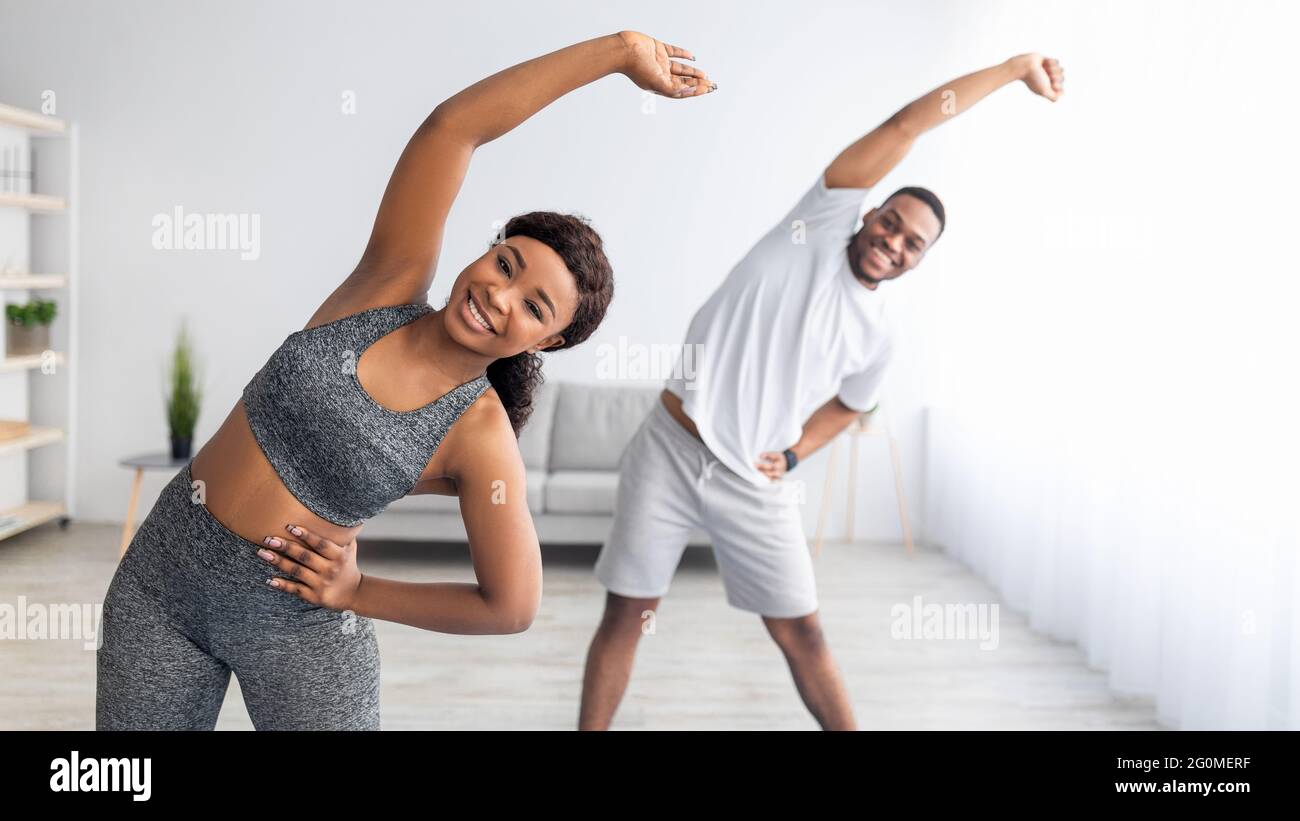 Millennial black couple doing lateral flexion exercise, working out ...