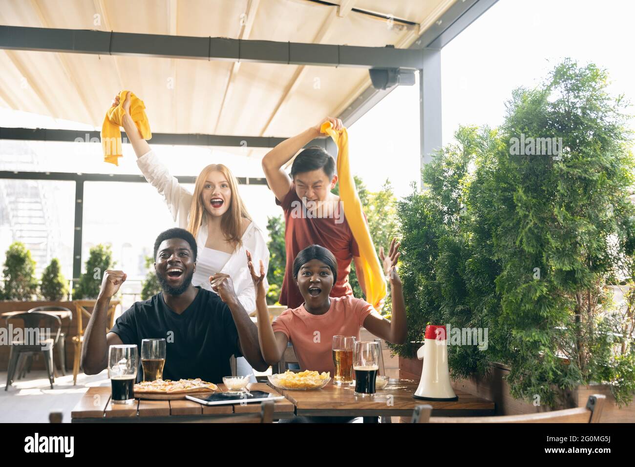 Four young people, sportive fans meeting together in bar, pub. Concept ...