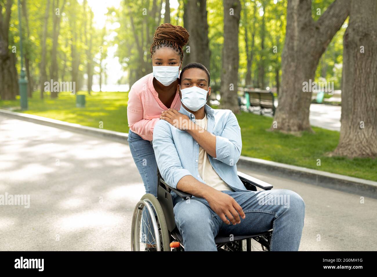Millennial black woman hugging her handicapped boyfriend in wheelchair ...