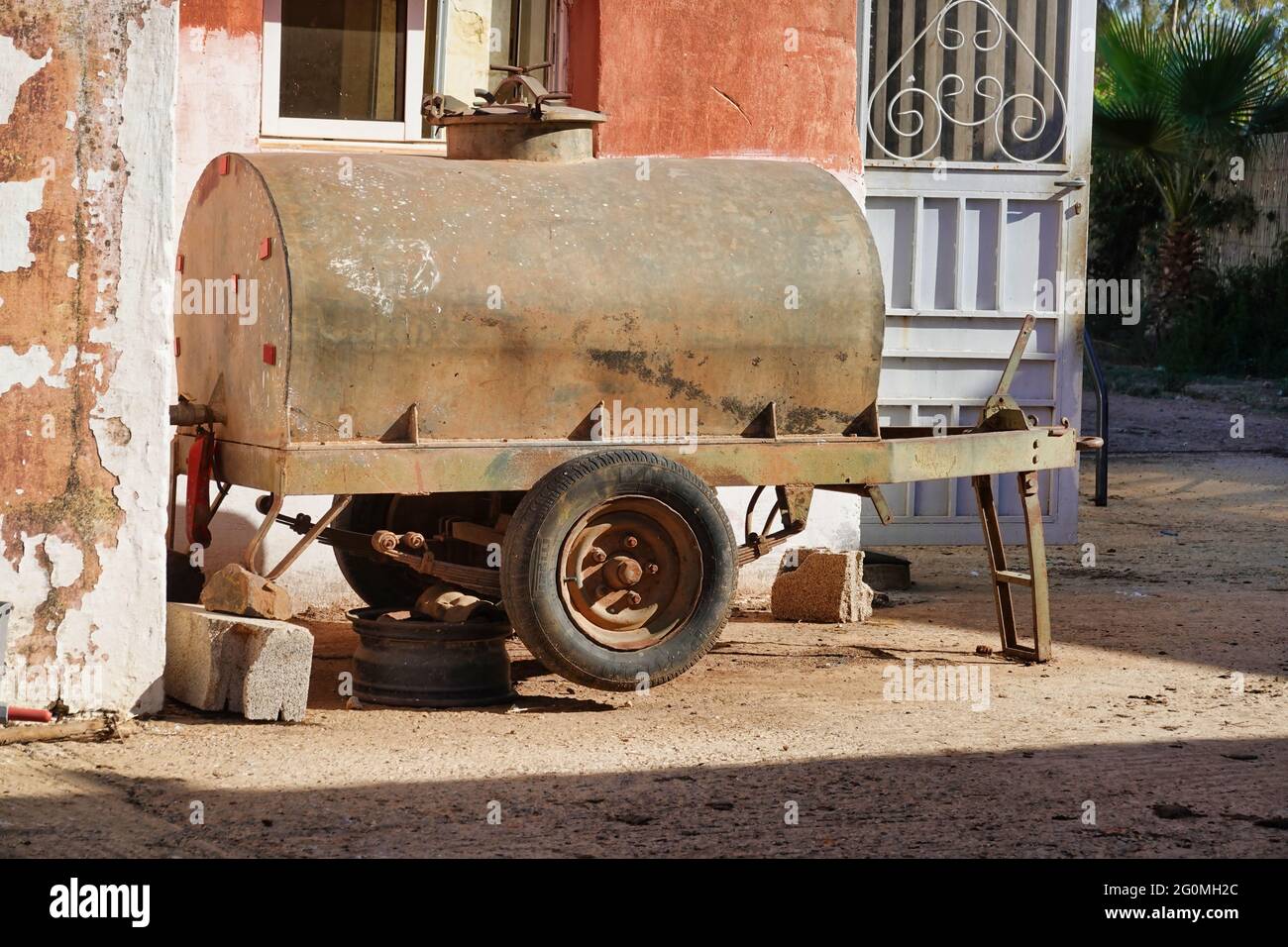 Side view of old rusty metal barrel trailer put outside next to the ...