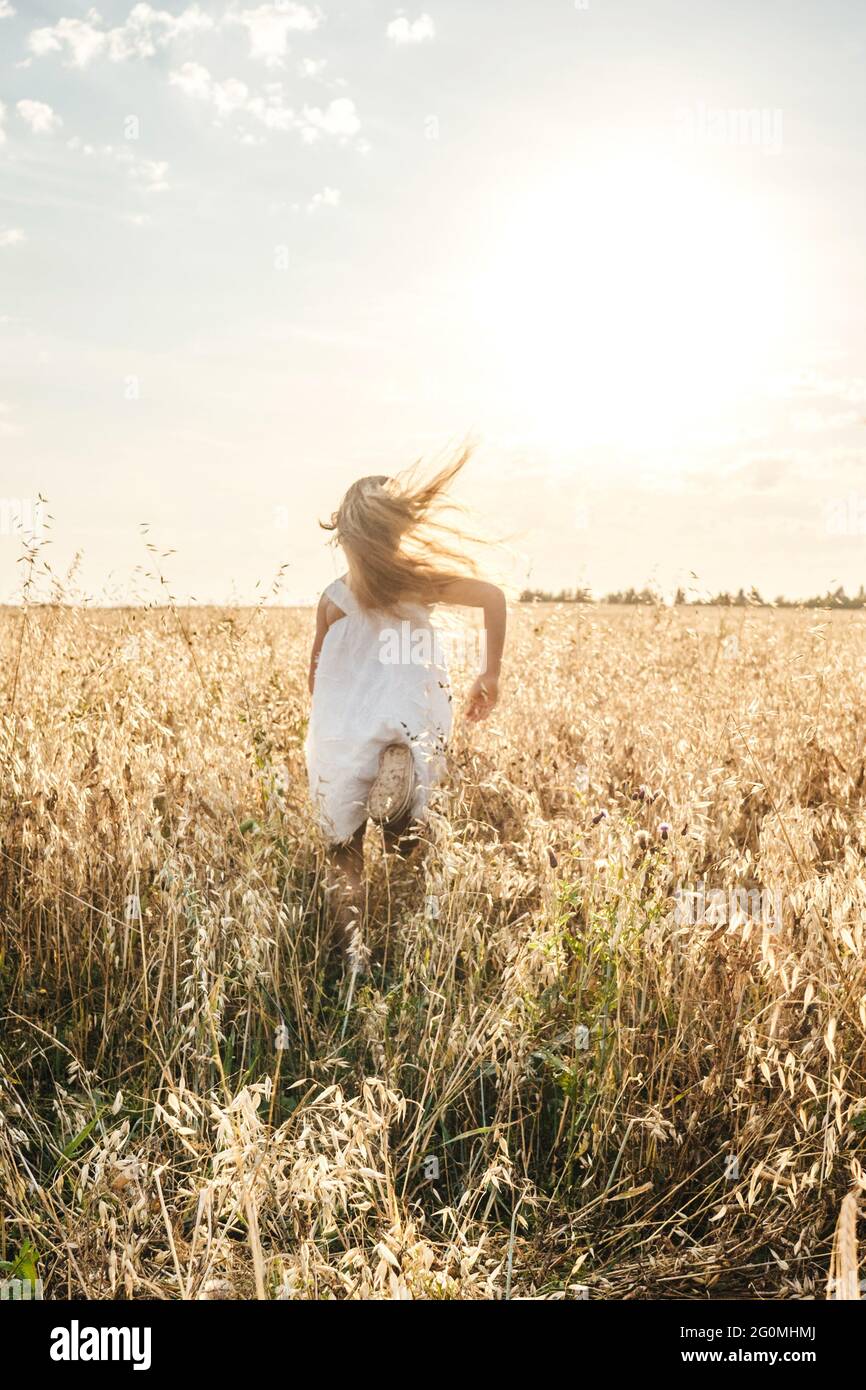 Little girl running on meadow in the distance. Sunset light, copy space ...