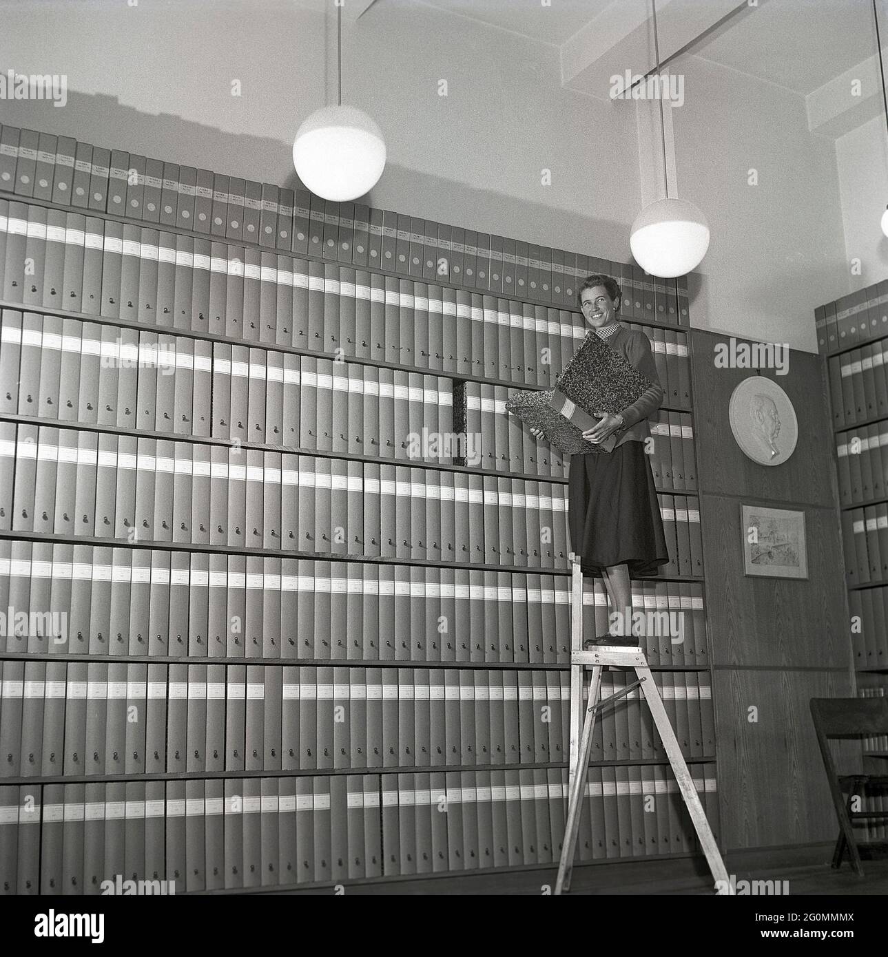 1950s woman at work. A young woman is standing on a ladder in an ...