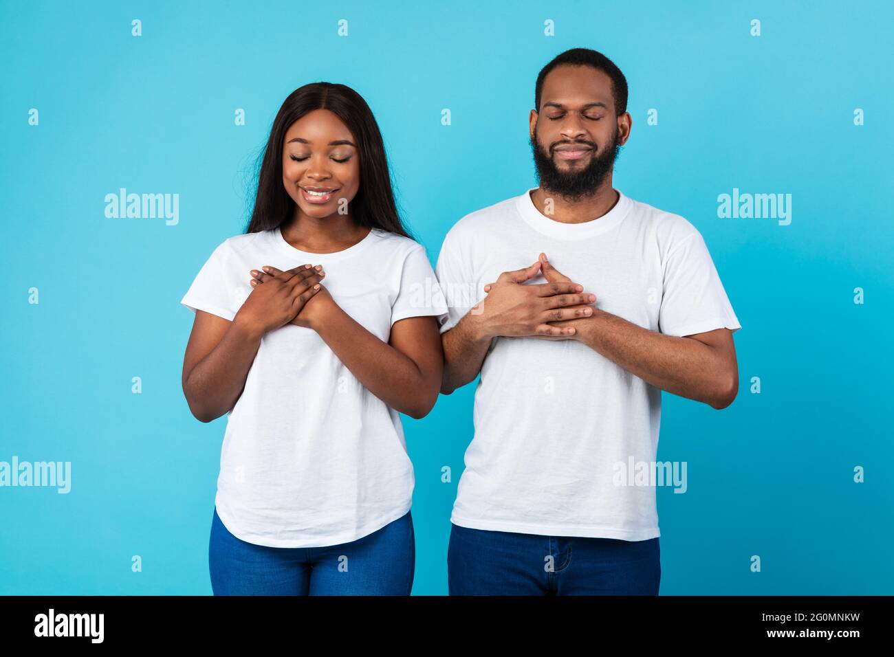 Black couple keeping hands on chest at studio Stock Photo - Alamy