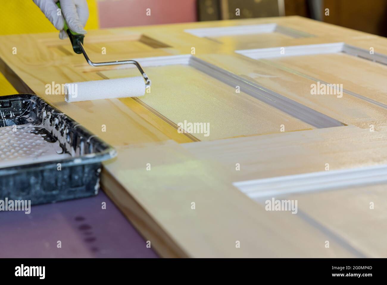 Man painting a wooden door using paint roller with carpenter working ...