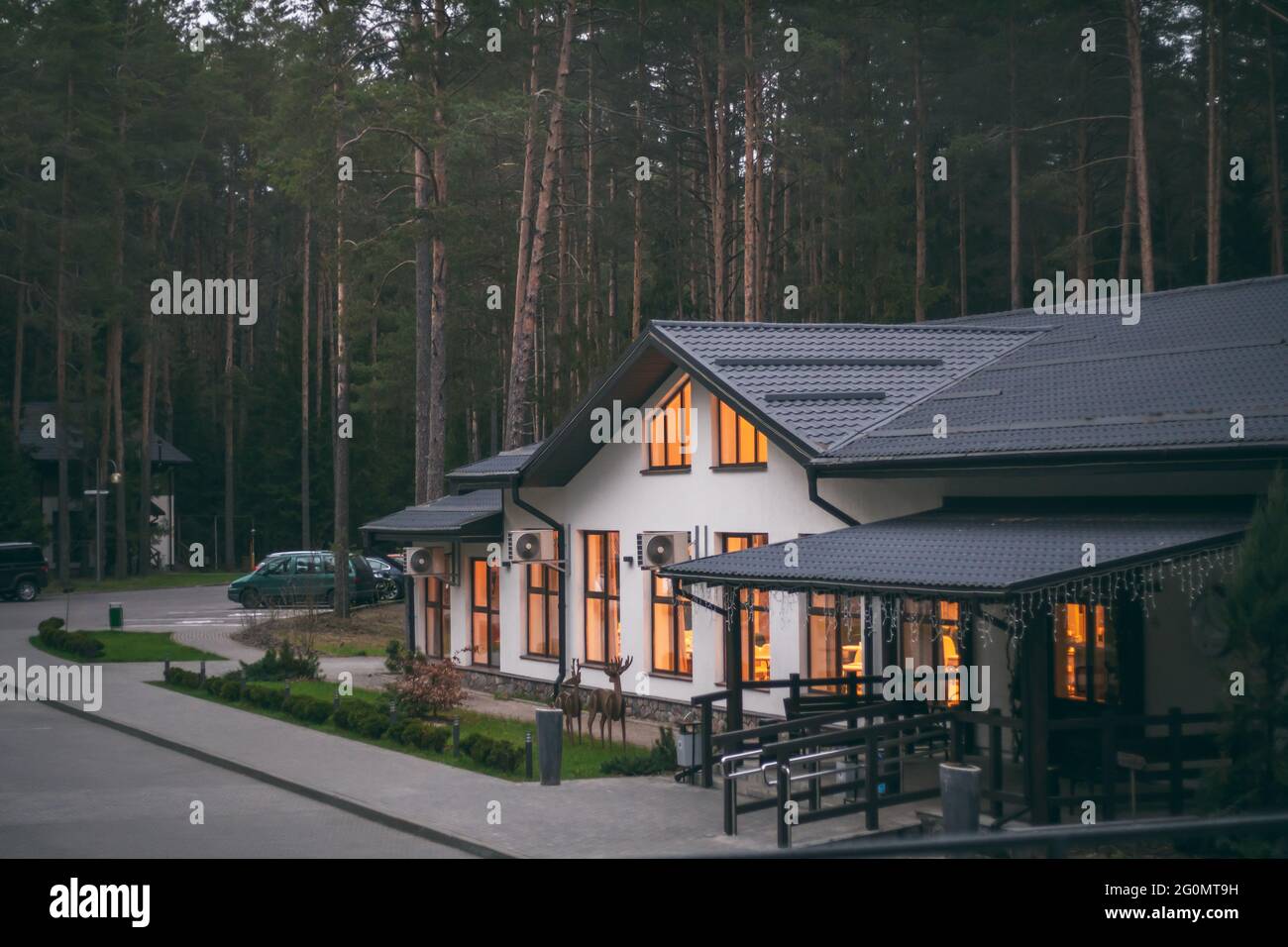 White restaurant building with gable roof in pine forest, with burning ...