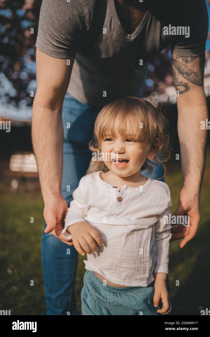 A father supports his child who is learning to walk Stock Photo - Alamy