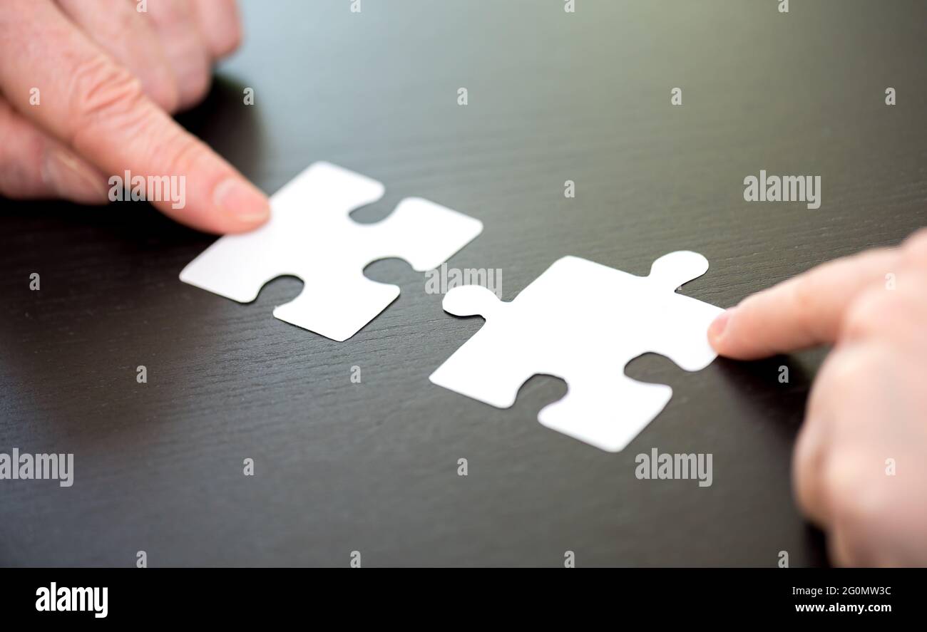 Hands joining two puzzle pieces, teamwork concept Stock Photo - Alamy