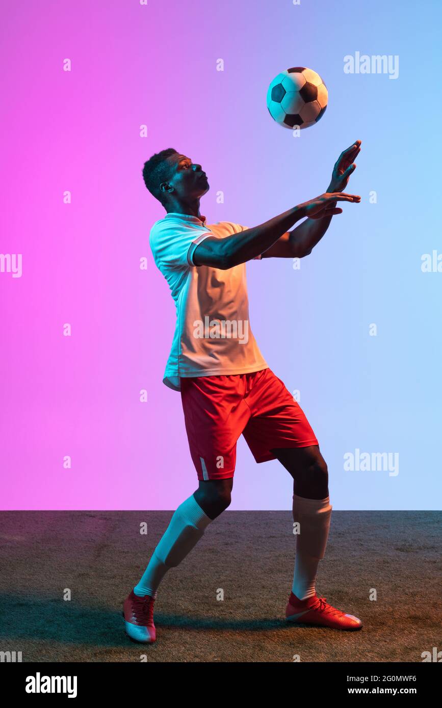 Portrait of African professional football player standing isolated on ...