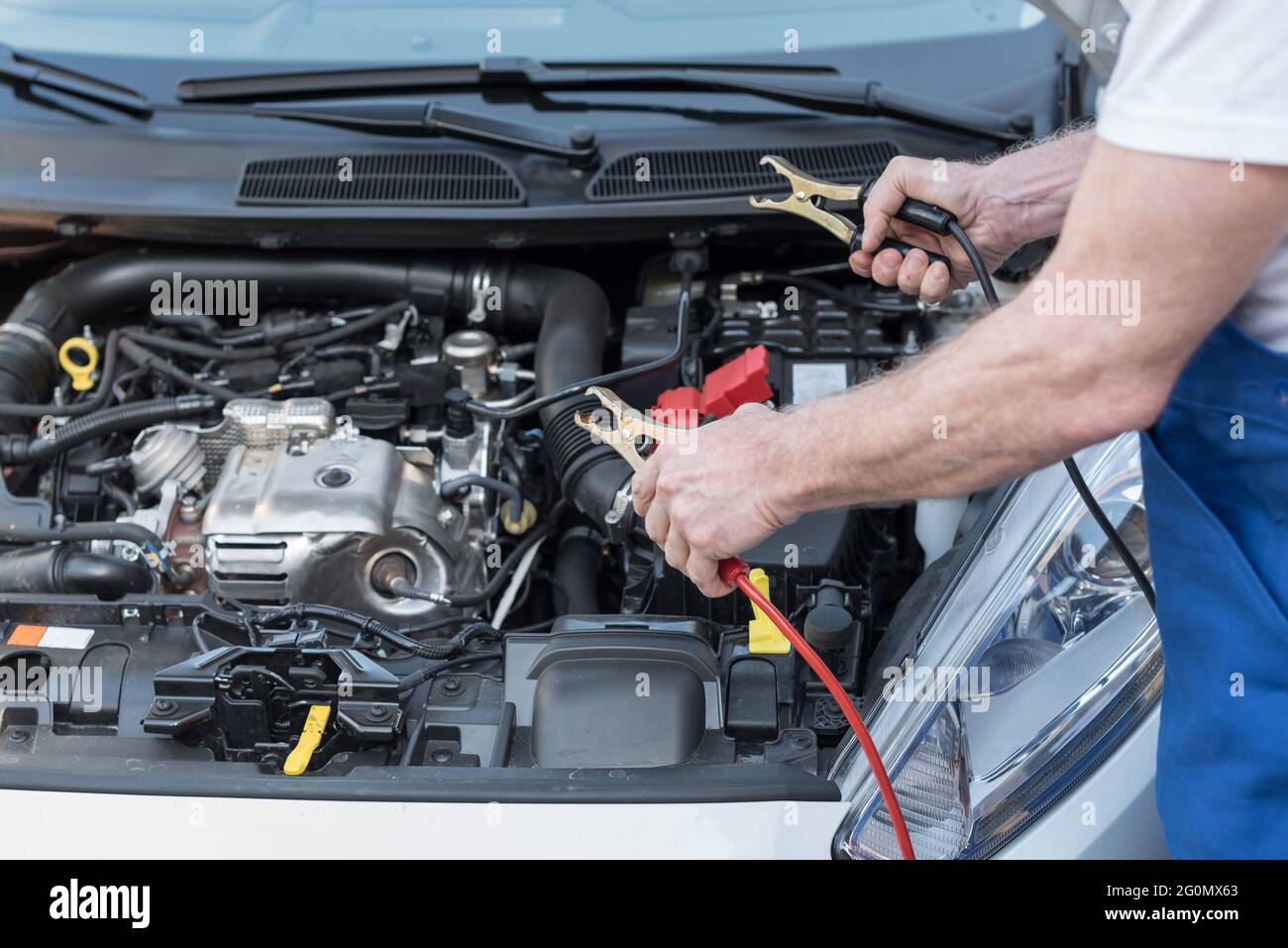 Car mechanic using cables to start a car engine Stock Photo - Alamy