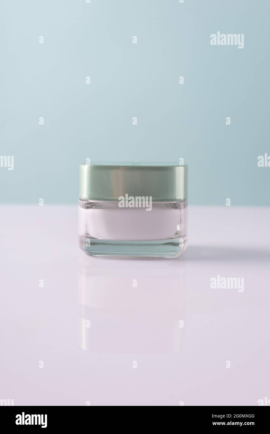 glass container of cosmetic white cream, on a white-blue background ...