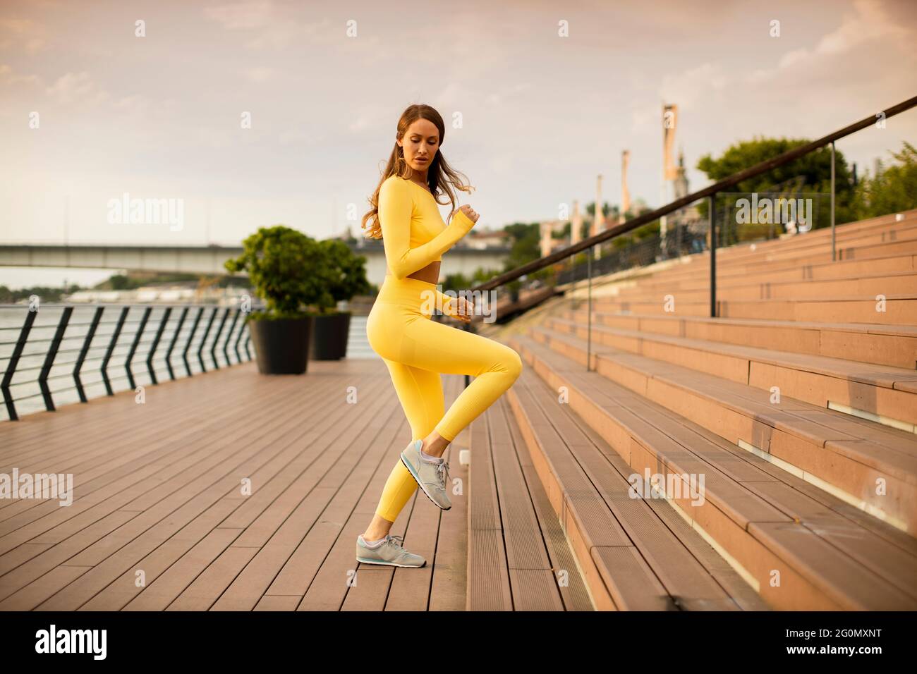 Pretty young womantaking exercises on the stairs by the river promenade ...