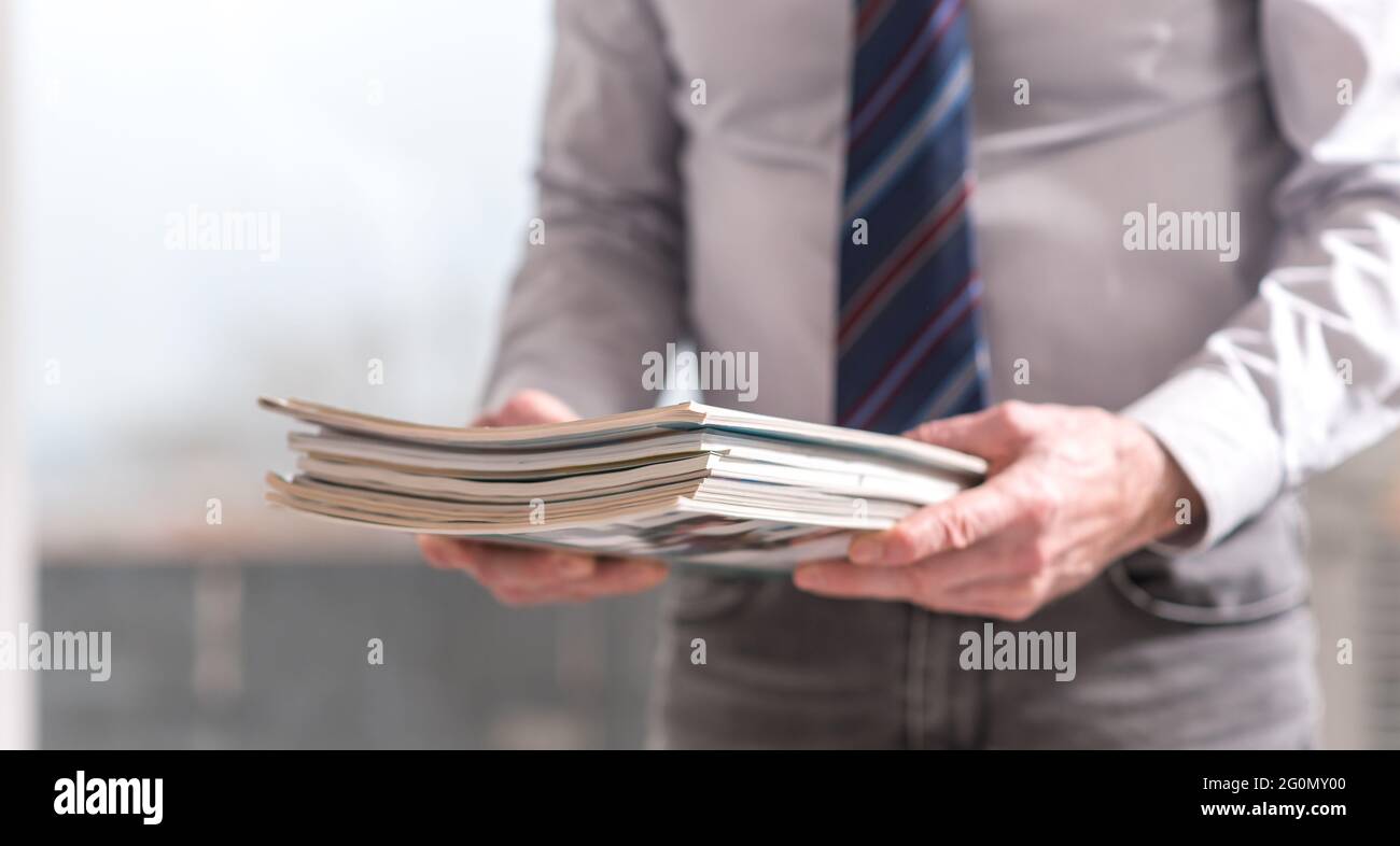 Hands of businessman holding magazines Stock Photo - Alamy