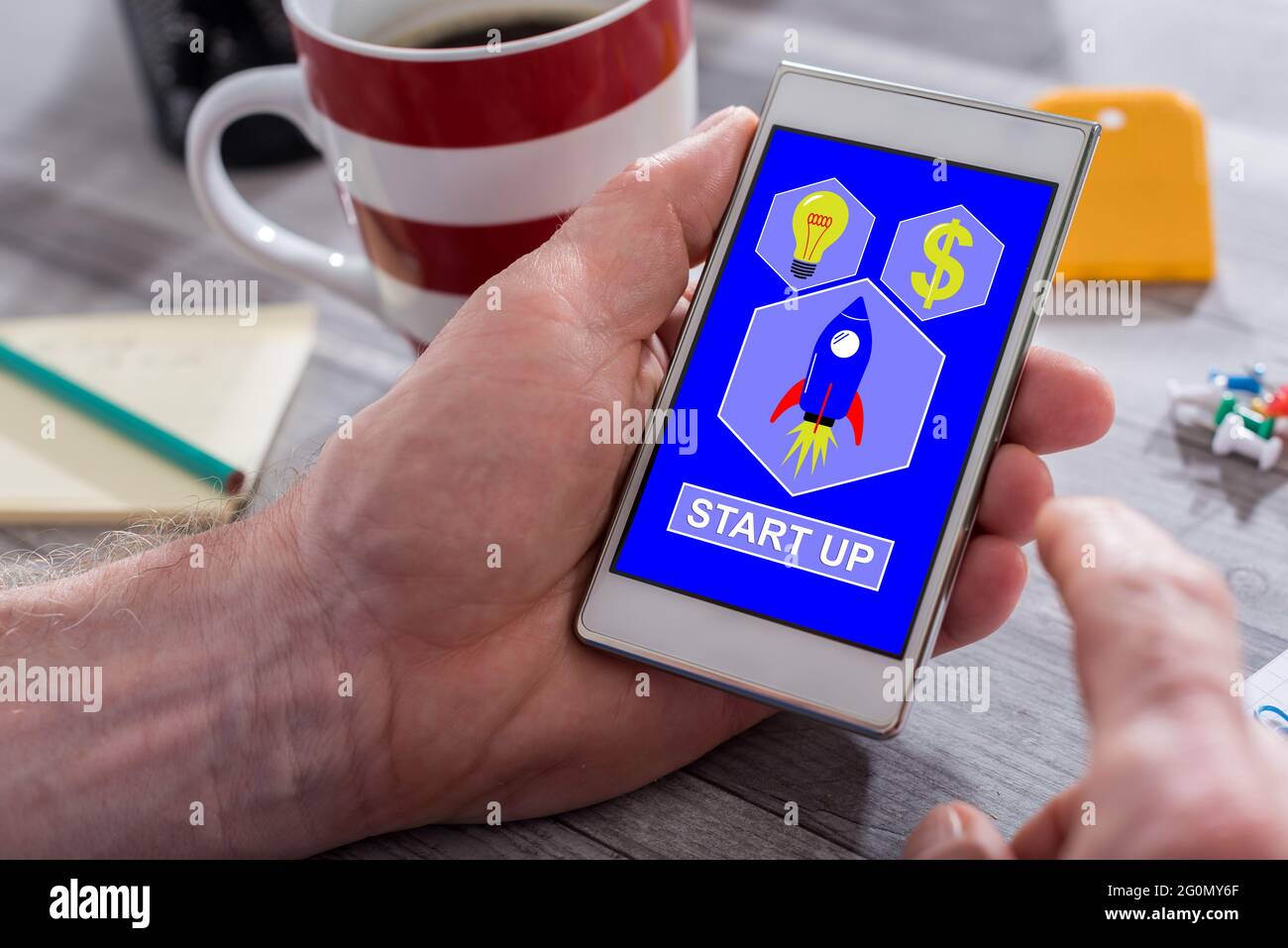 Male hand holding a smartphone with start up concept Stock Photo - Alamy