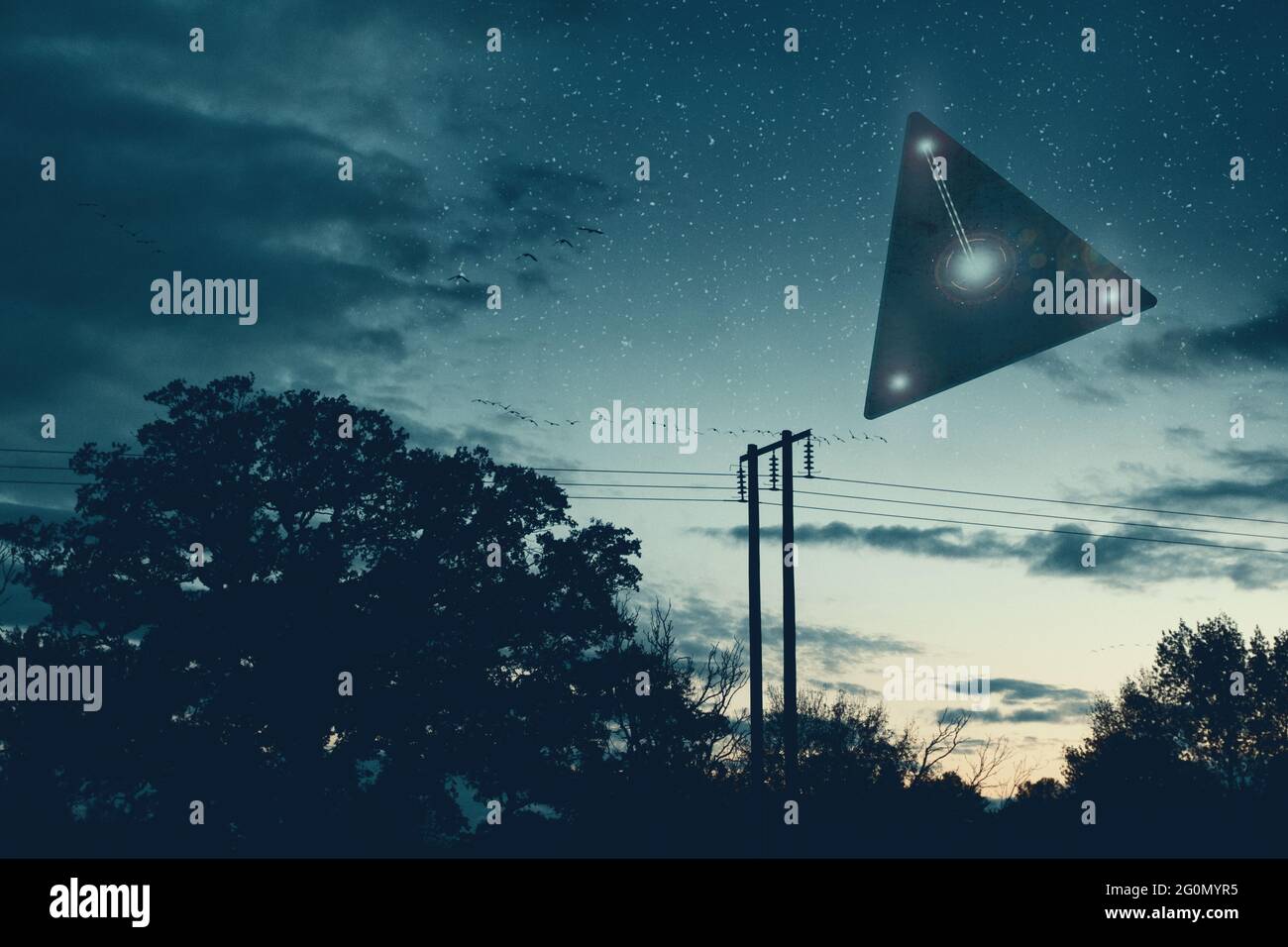 UFO concept. A flying triangle floating above the countryside at night ...