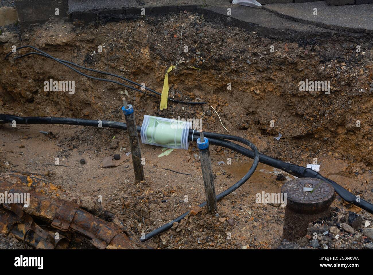 Dug up sidewalk revealing wires in protective tubes. Building of ...
