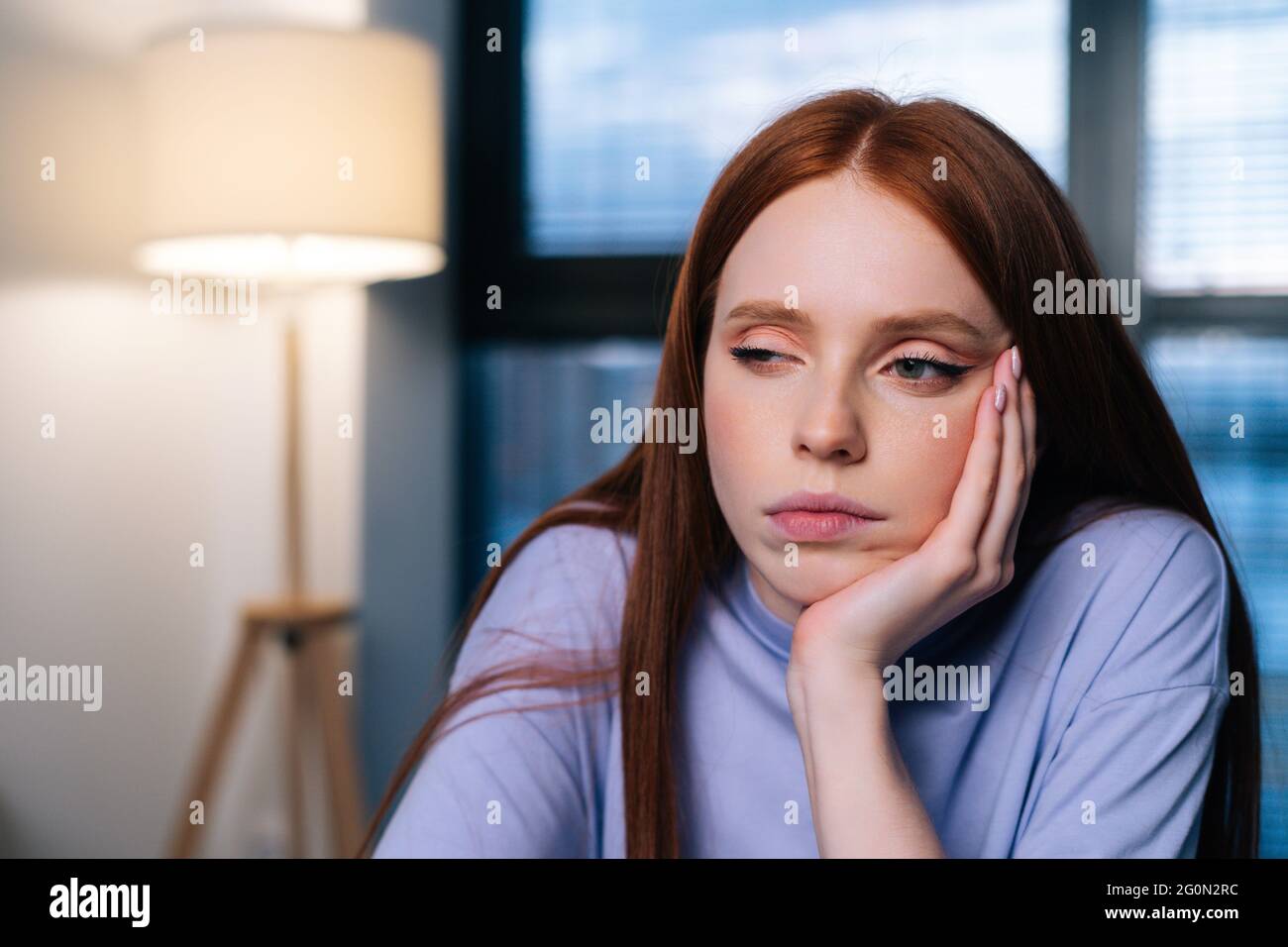 Close-up face of tired sad woman sitting at desk with laptop in dark ...