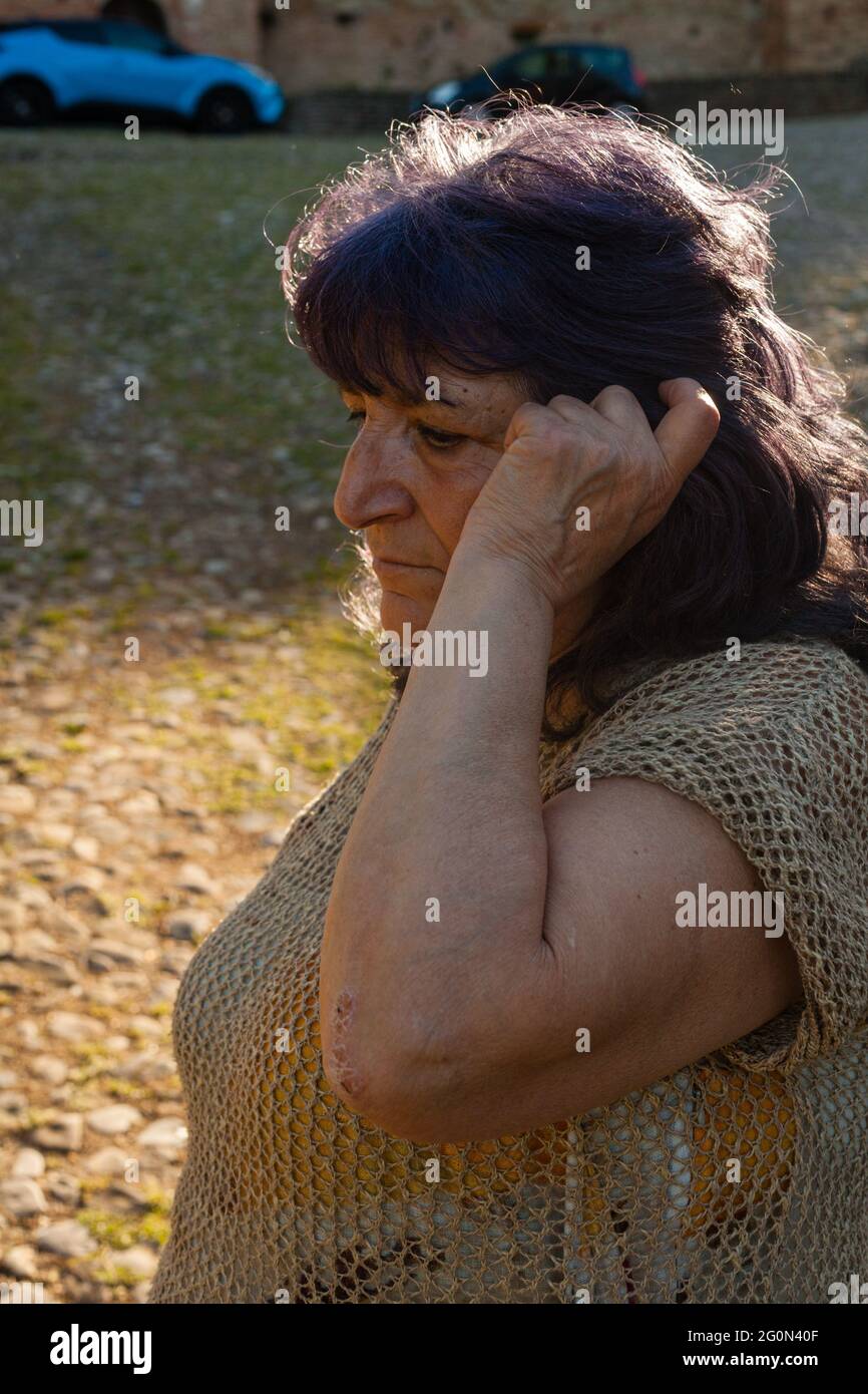 Portrait of a senior Hispanic female fixing her hair in the garden ...