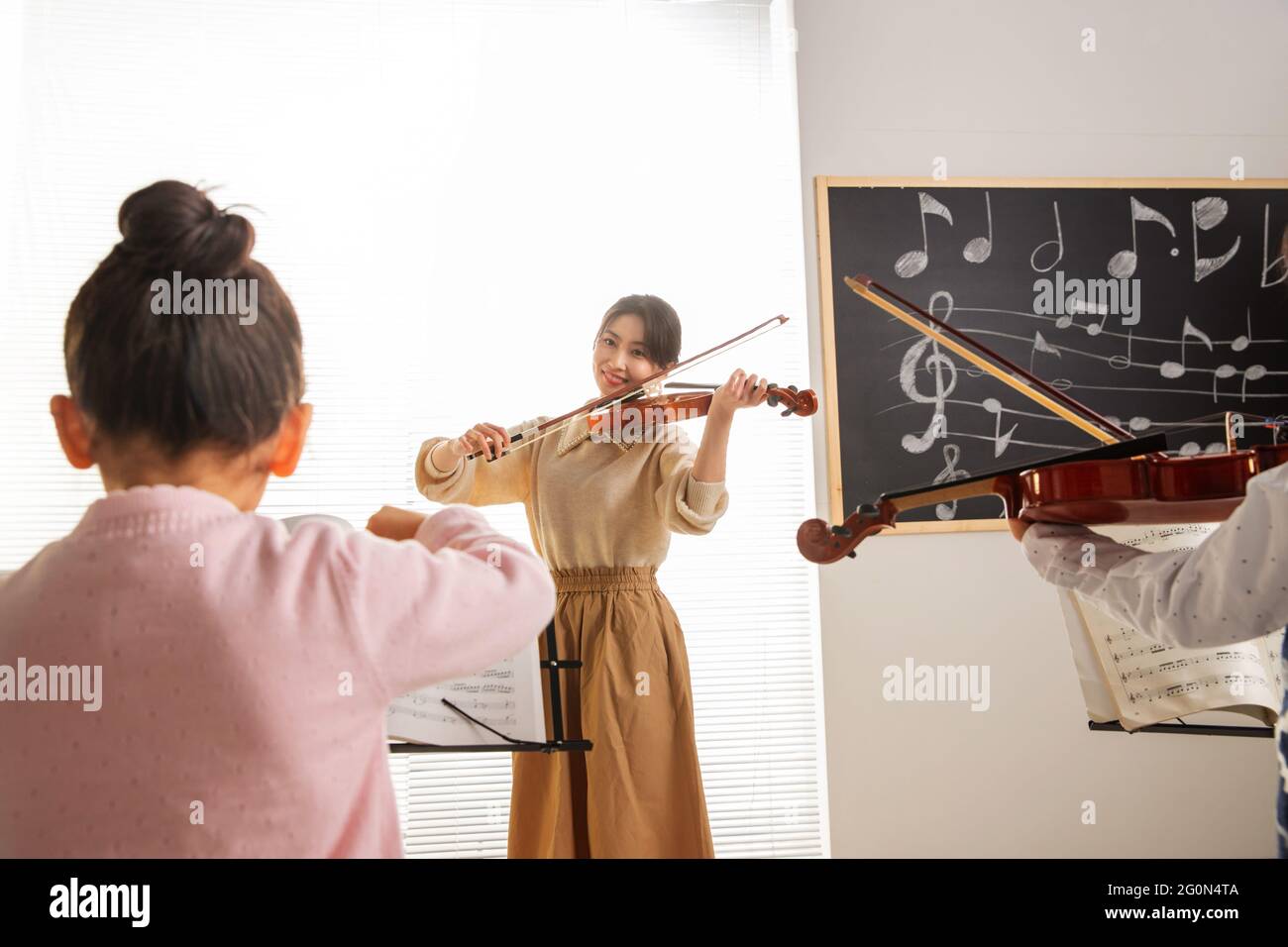 Young women teach children music lessons Stock Photo - Alamy