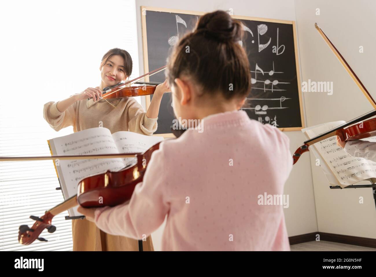 Young women teach children music lessons Stock Photo - Alamy