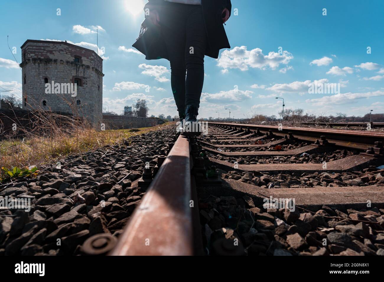 Young woman walking on the railroad tracks with Kula Nebojsa tower in ...
