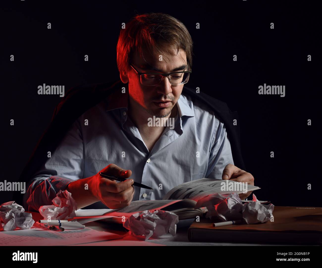 Adult man in shirt, jacket and glasses sits behind desk, table with ...