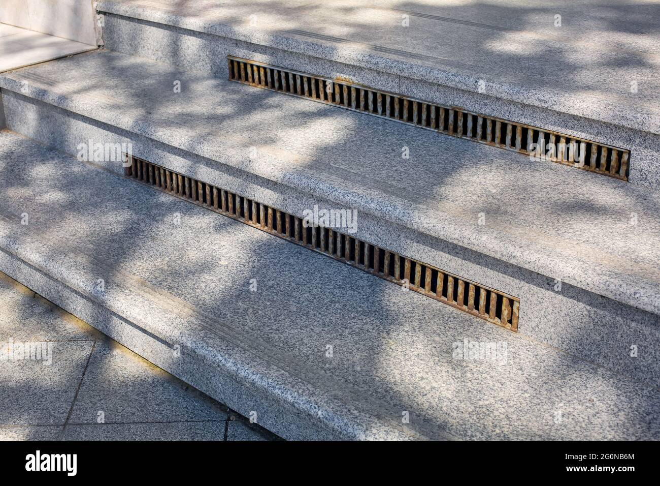 a stone staircase with gray granite steps and a drainage grate to drain ...