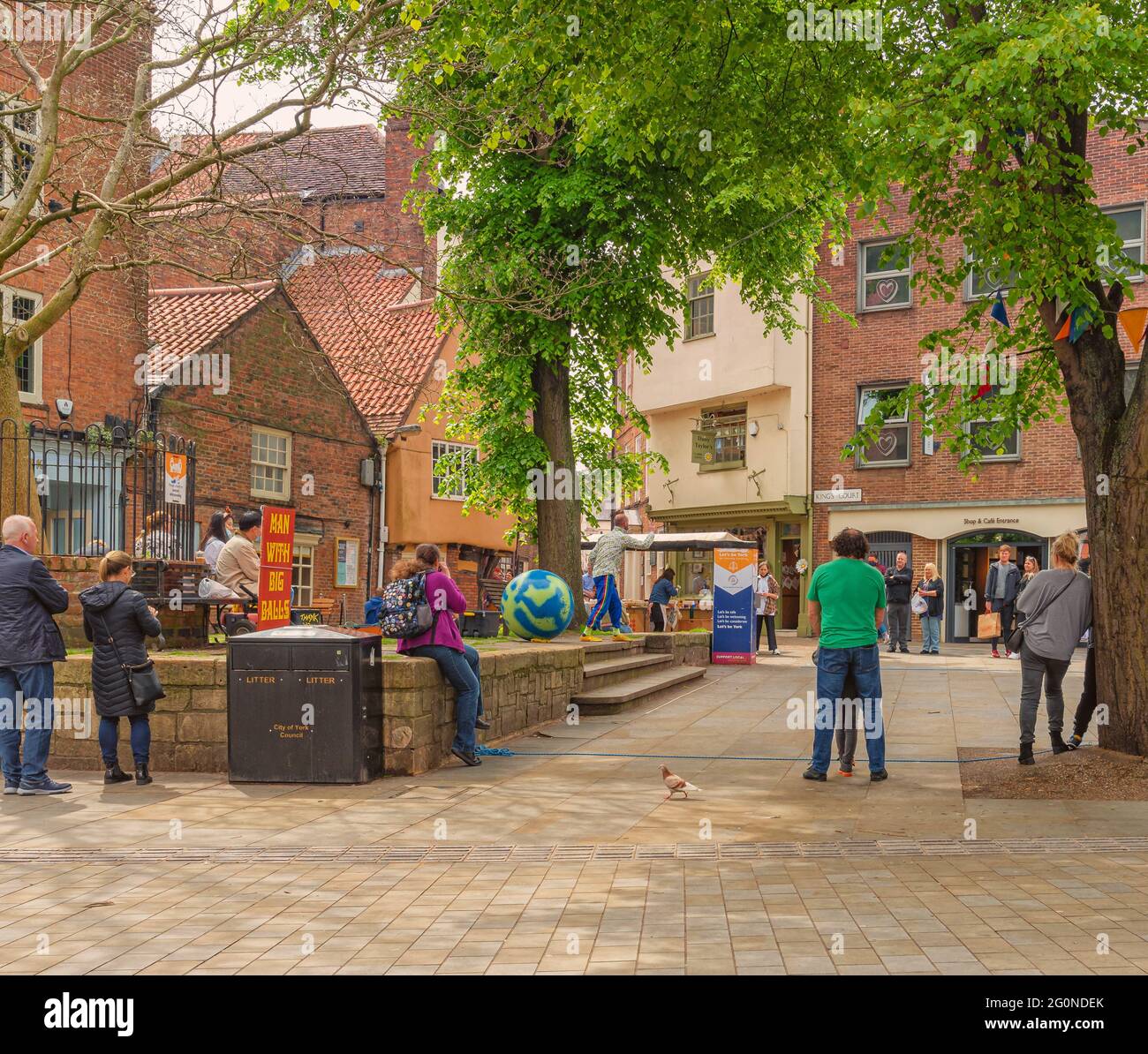 A tree overhangs a scene where a street performer attracts a small ...