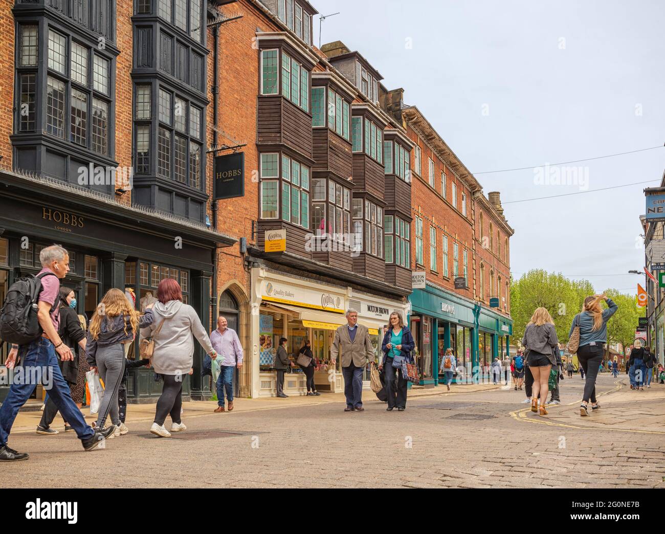 A busy city street with shops to the side. The street is cobbled and ...