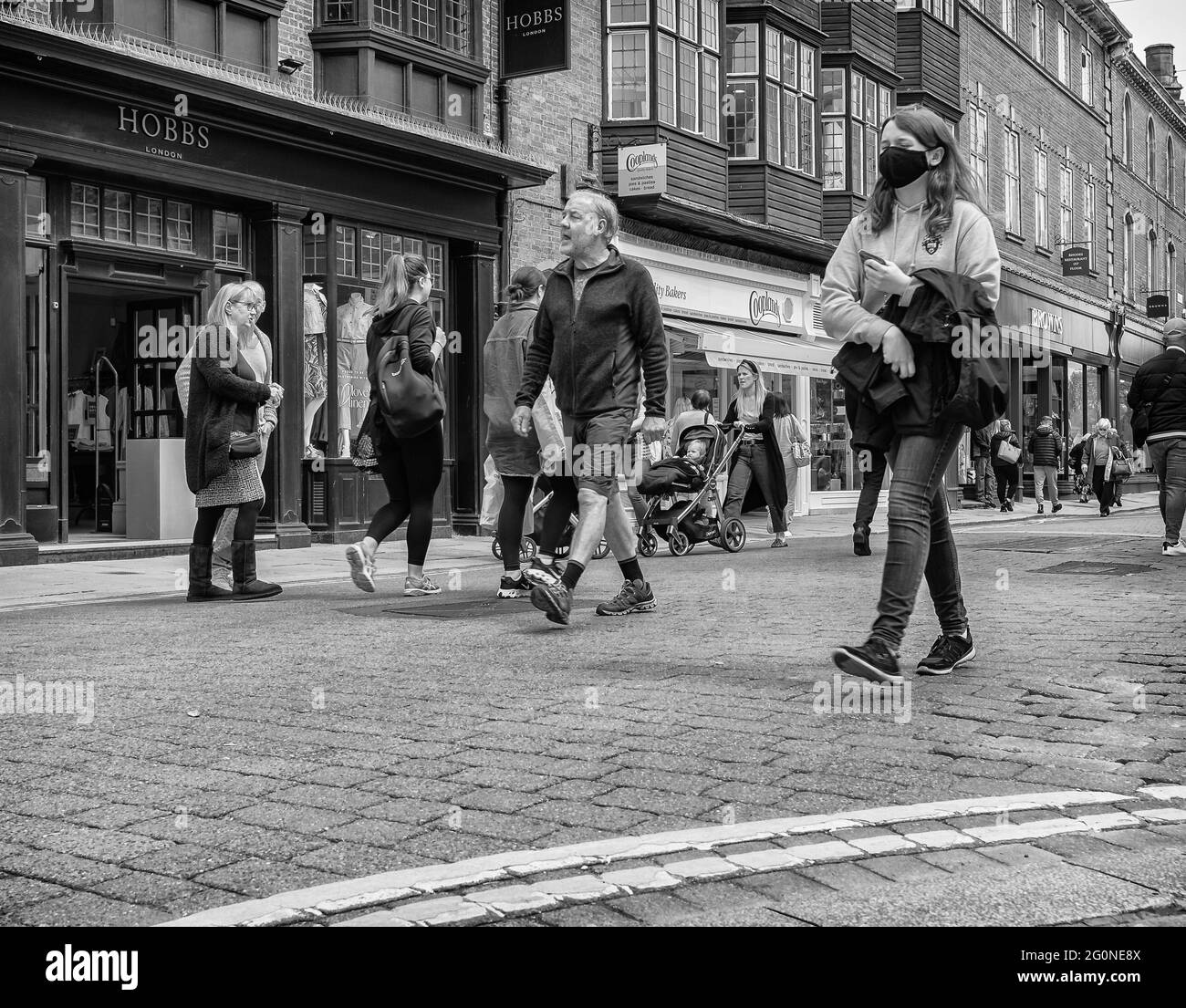 A busy city street with shops to the side. The street is cobbled and ...