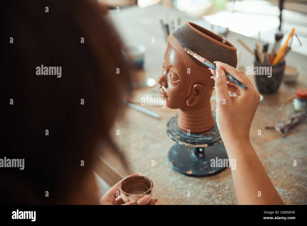 Female ceramist hand painting pottery in workshop Stock Photo - Alamy