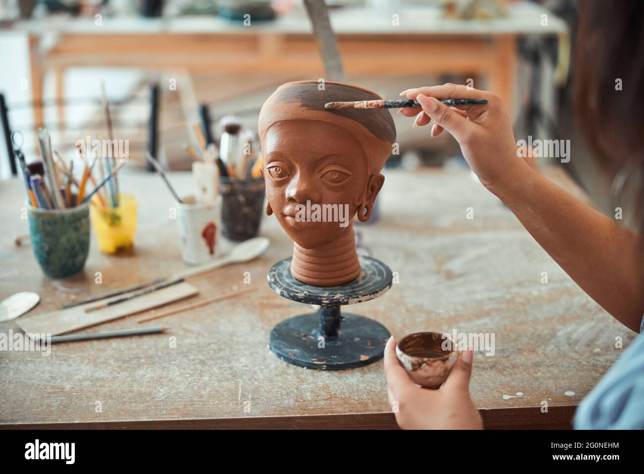 Female ceramist painting on clay sculpture in workshop Stock Photo - Alamy