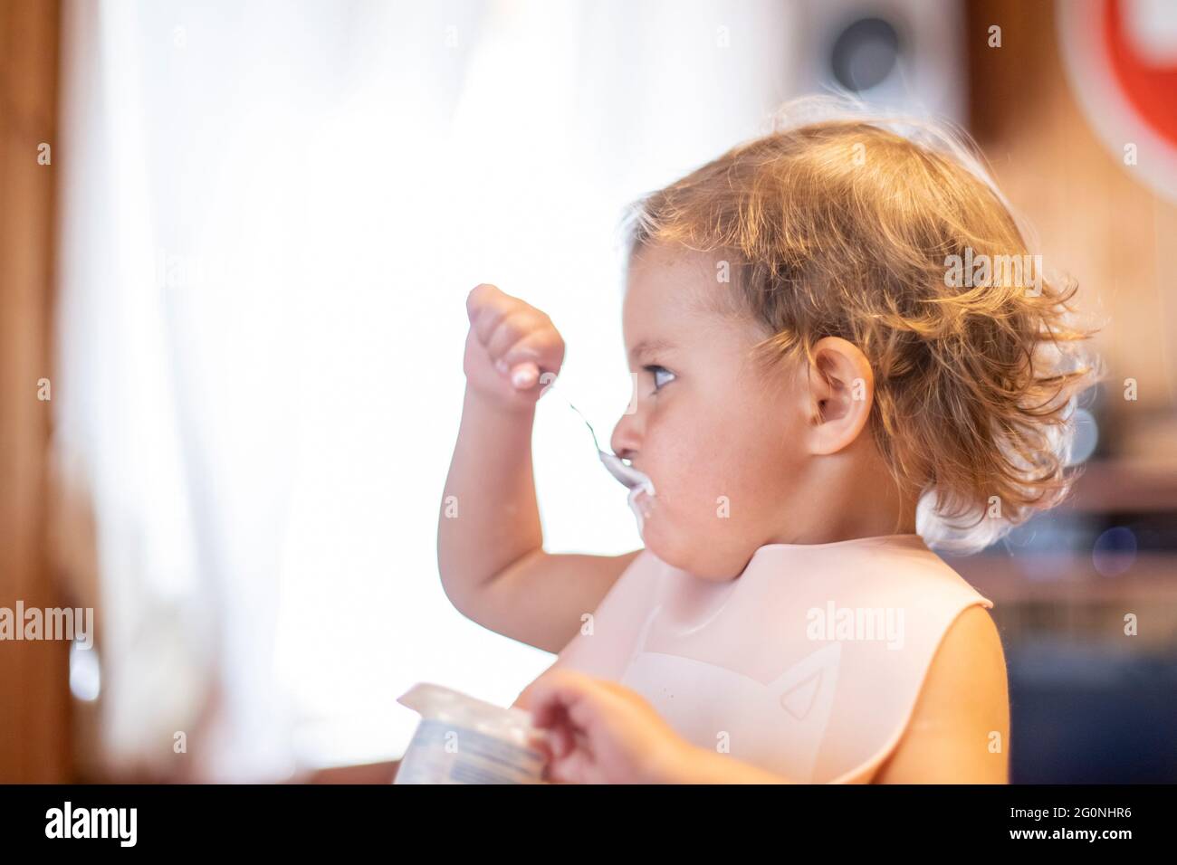 cute baby eating yogurt with spoon by himself. adorable toddler has ...