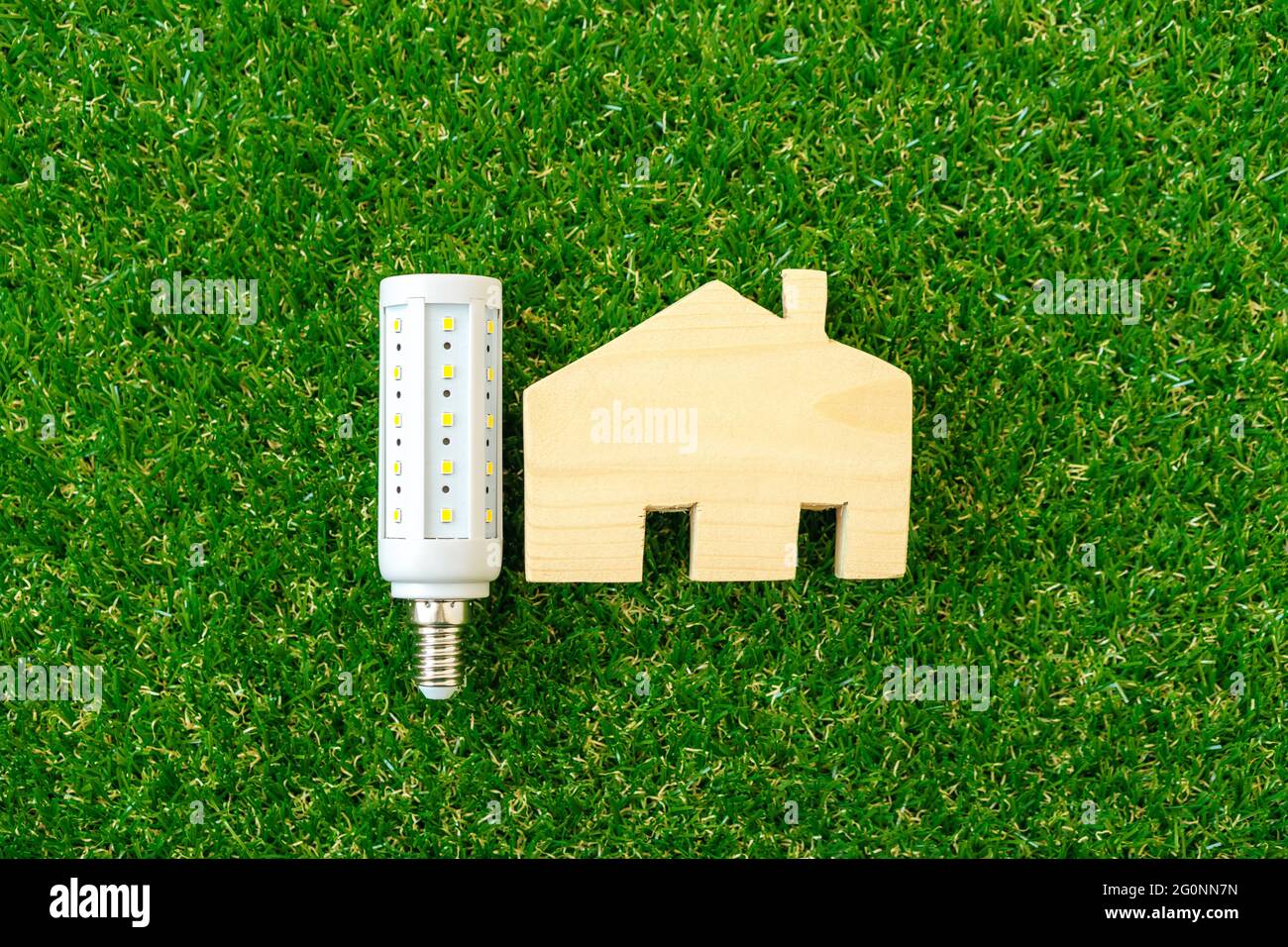 Wooden house model and lightbulb on green background Stock Photo - Alamy