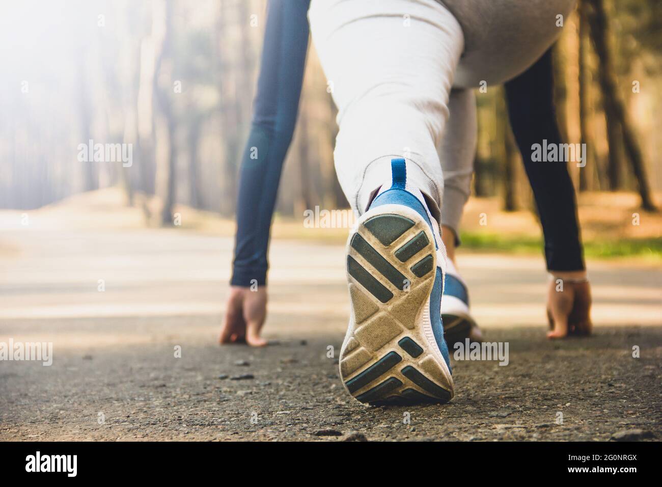 The girl prepares to run. Legs close-up on a forest background. Athlete ...