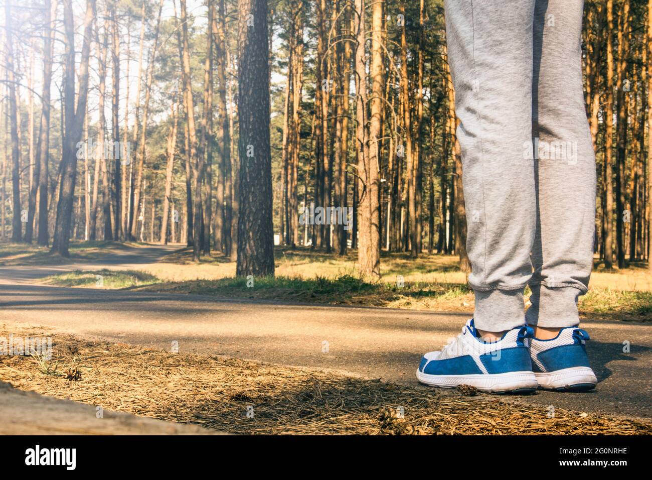 A sports girl stands in the forest. Legs in sneakers close-up on a ...