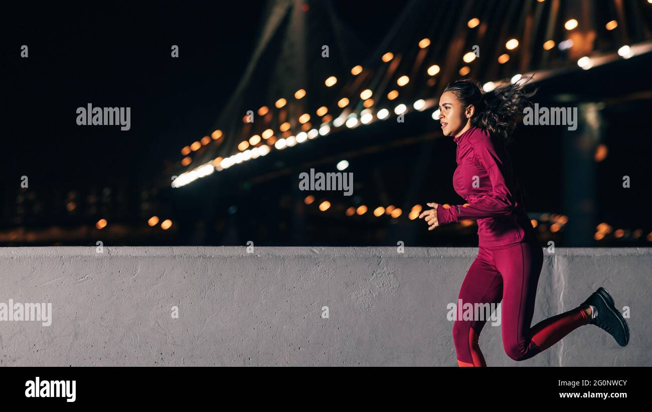 Mixed race woman in sports clothes running at night outdoors Stock ...