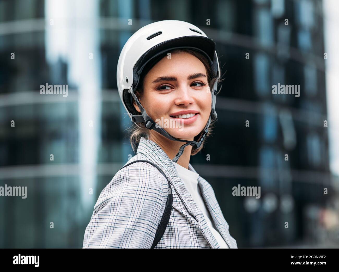 Portrait of a smiling woman wearing cycling helmet standing in front of ...