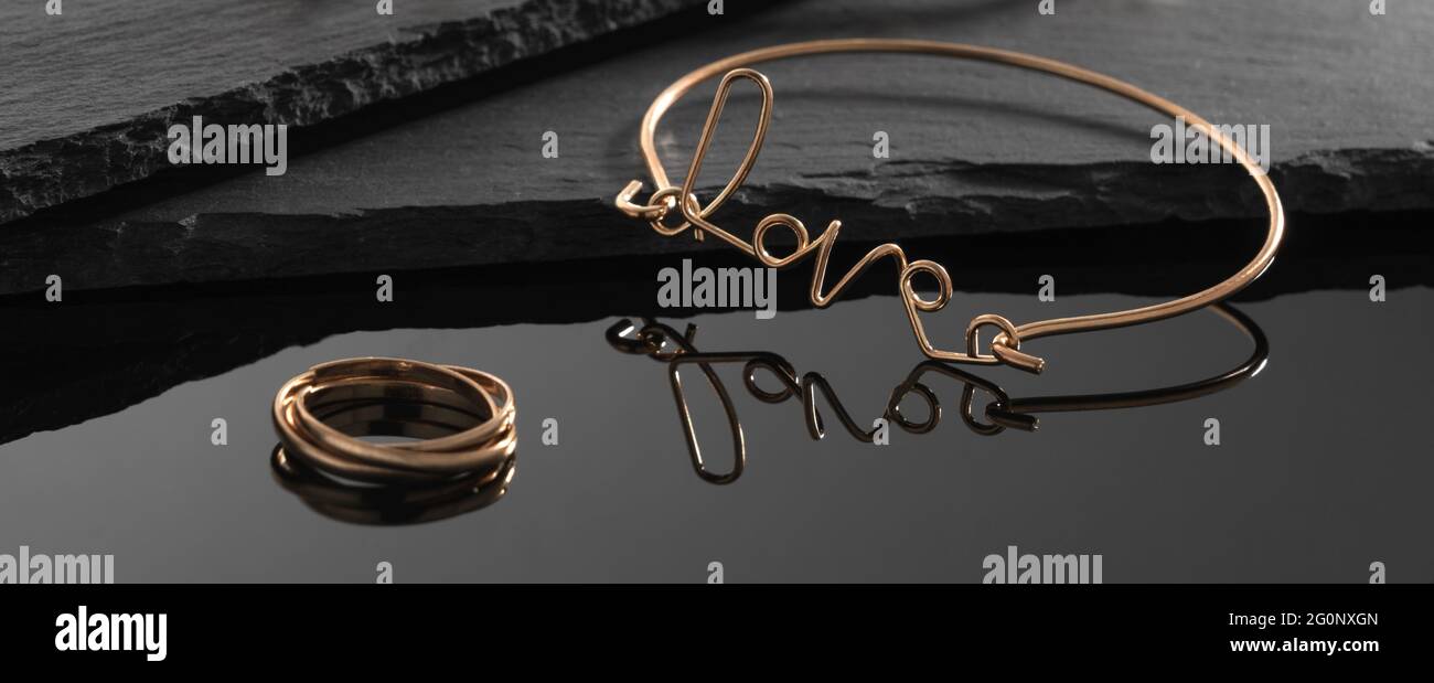 Love word shape bracelet and modern ring on dark background Stock Photo ...