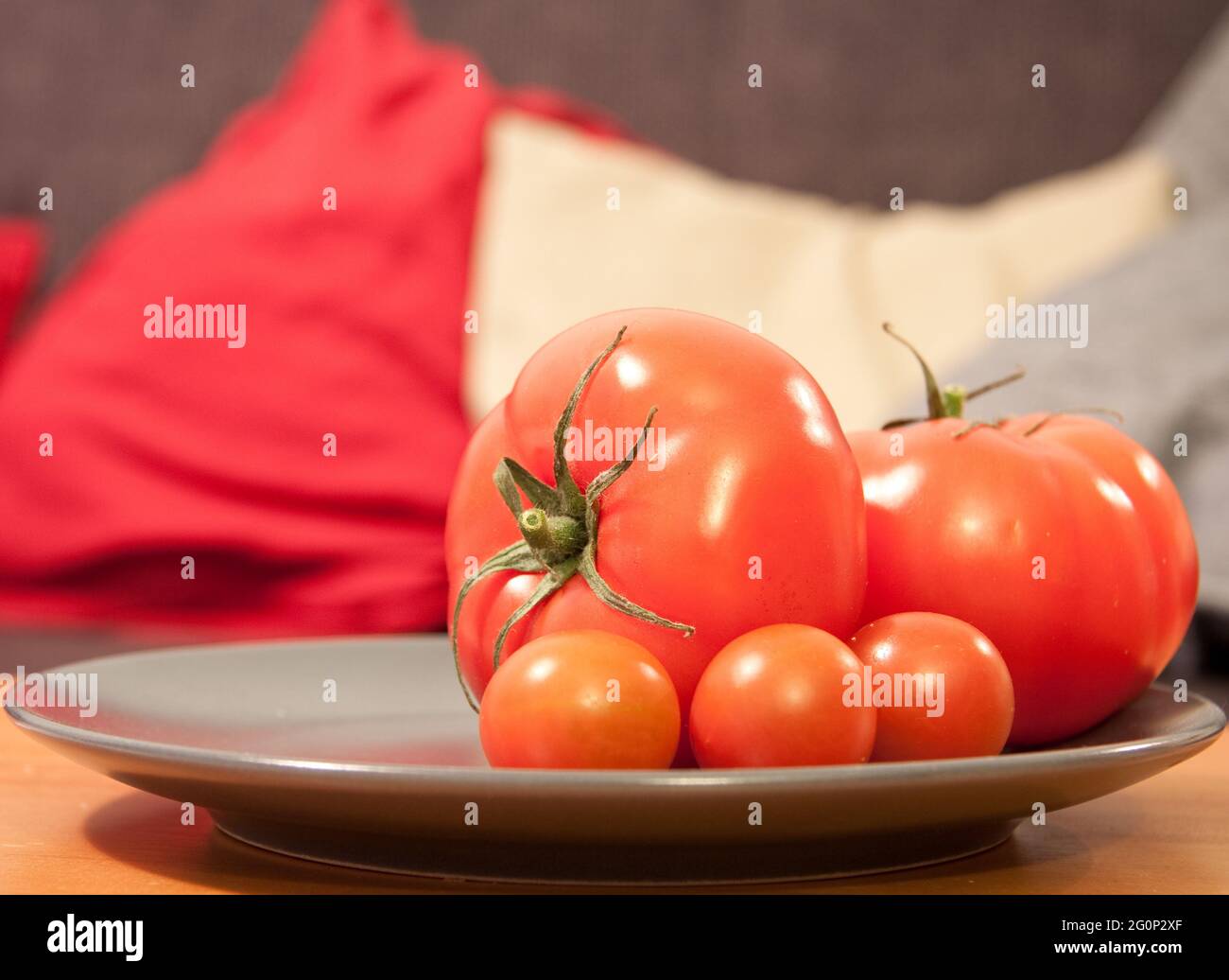 Closeup shot of juicy tomatoes in a black plate in the kitchen Stock ...