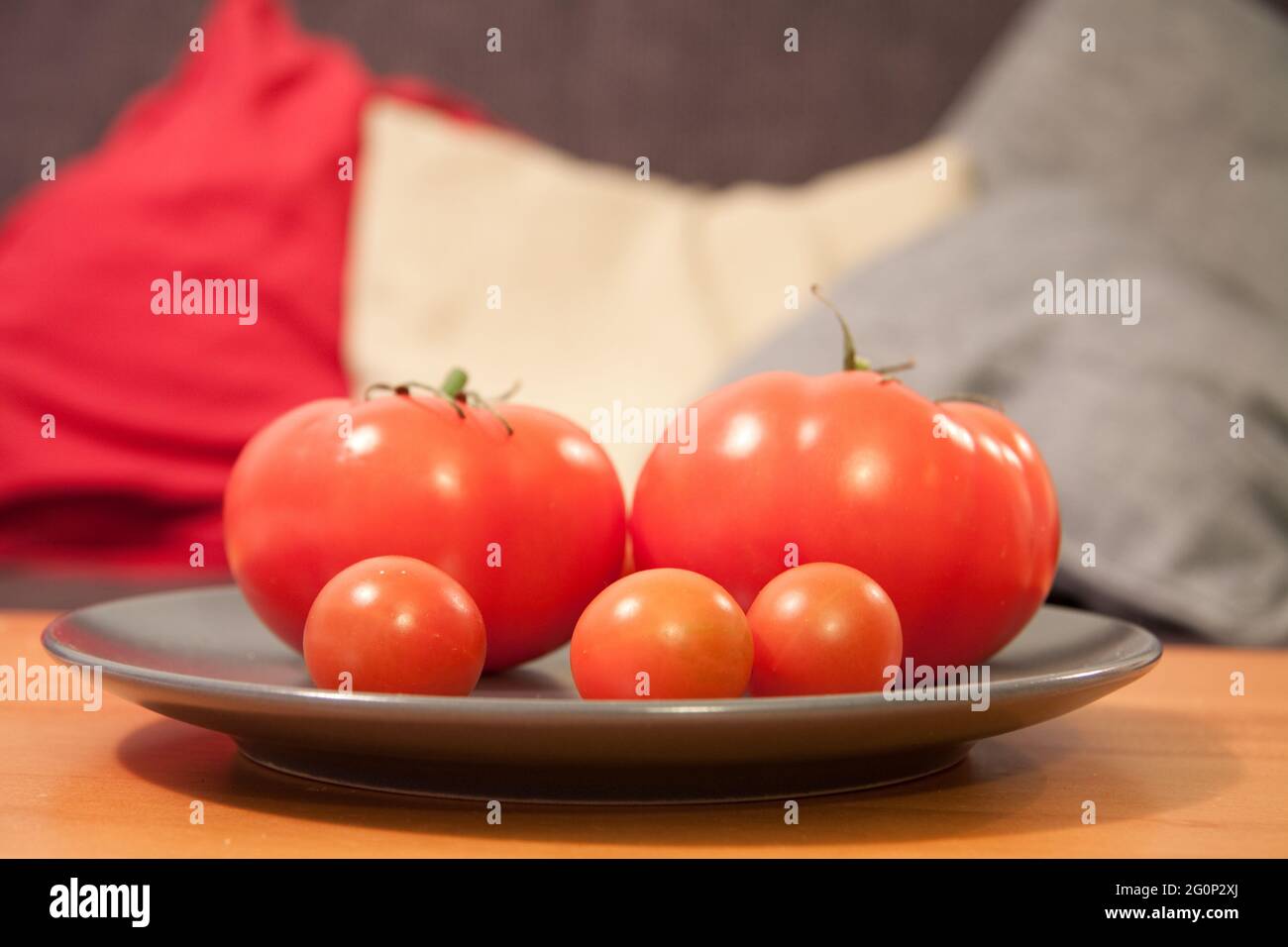Closeup shot of juicy tomatoes in a black plate in the kitchen Stock ...