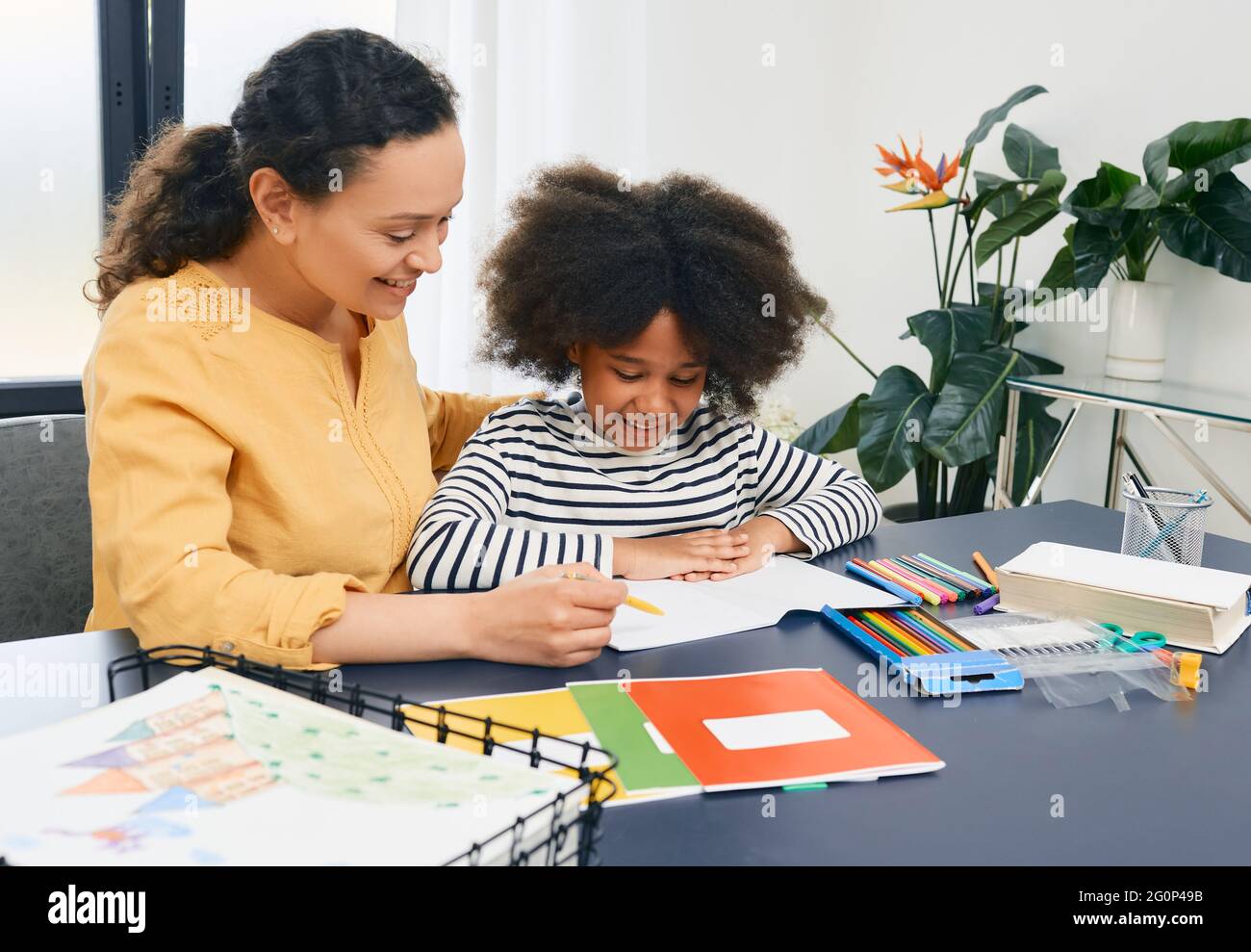 Mom helps her daughter doing school homework at home. Happy mother and ...