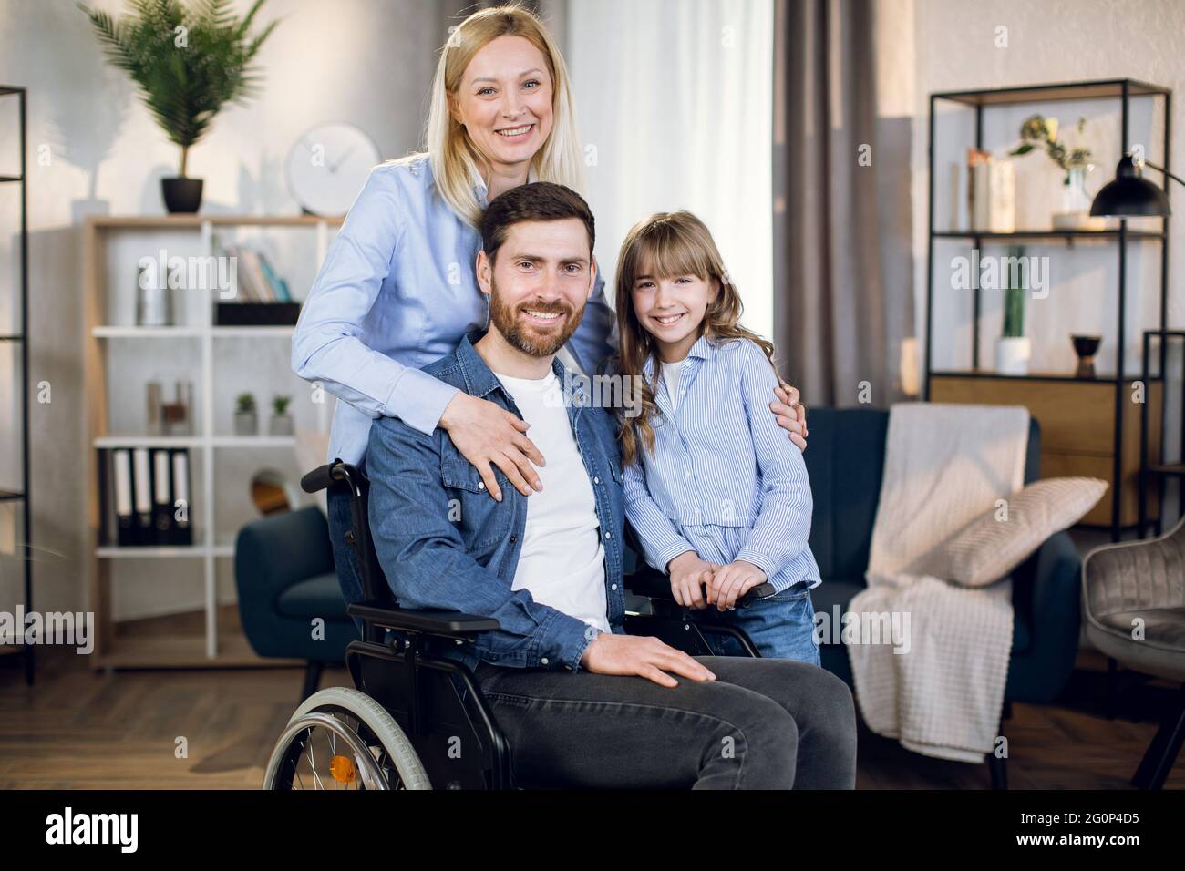 Disabled man sitting in wheelchair while his wife and daughter standing ...